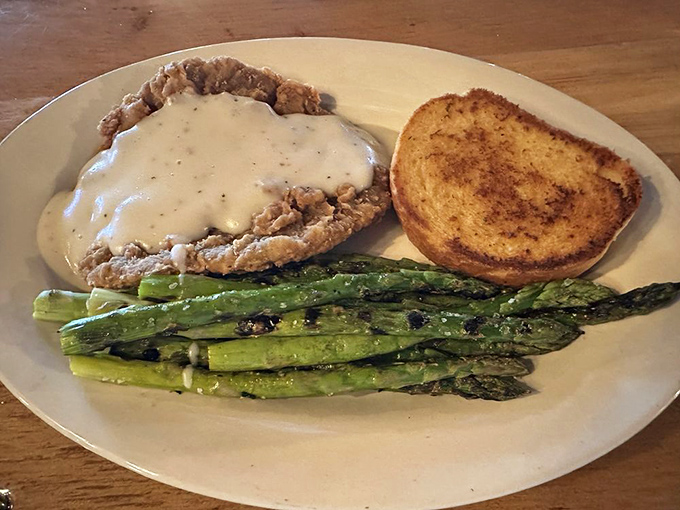 Country-fried steak smothered in peppery gravy alongside grilled asparagus&mdash;comfort food that hugs your insides like a warm Western blanket.