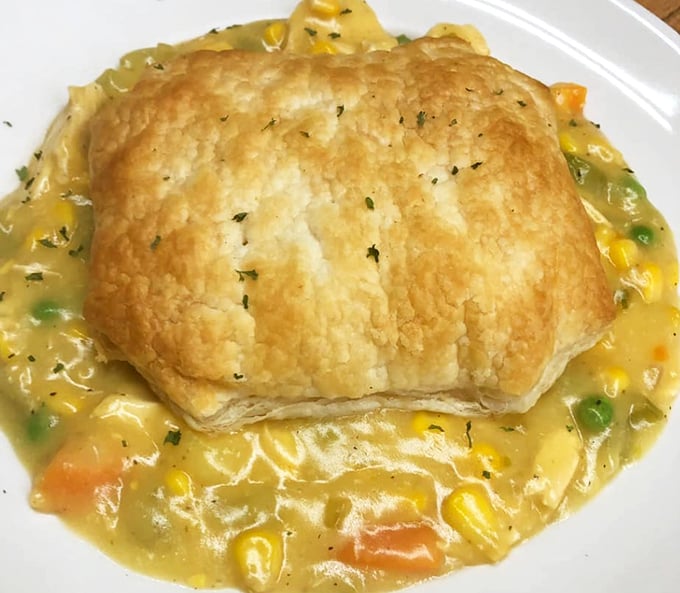 Golden-topped chicken pot pie arrives looking like grandma's recipe came to life, complete with vegetables peeking through flaky crust.