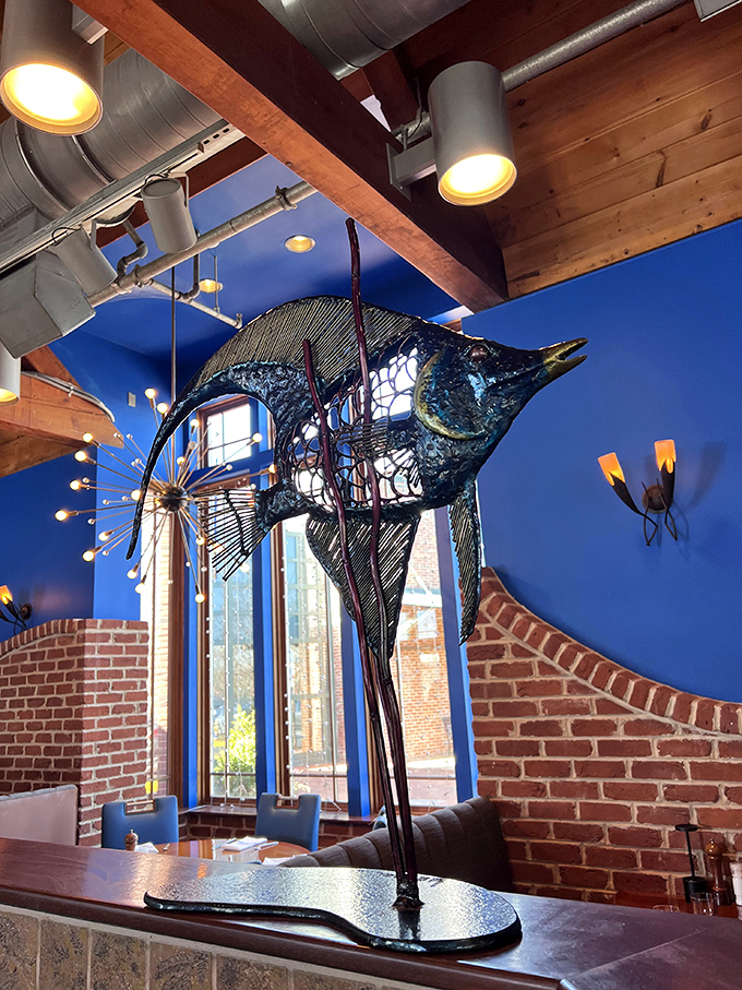 This sculptural marlin stands as both art and guardian of good taste &ndash; a metallic sentinel watching over diners from its perch against vibrant blue walls.