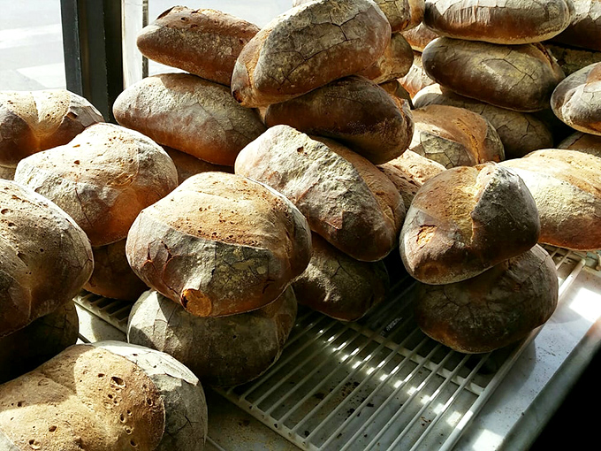 Fresh bread loaves piled high, crusty and golden, still warm enough to fill the whole bakery with heavenly aroma.