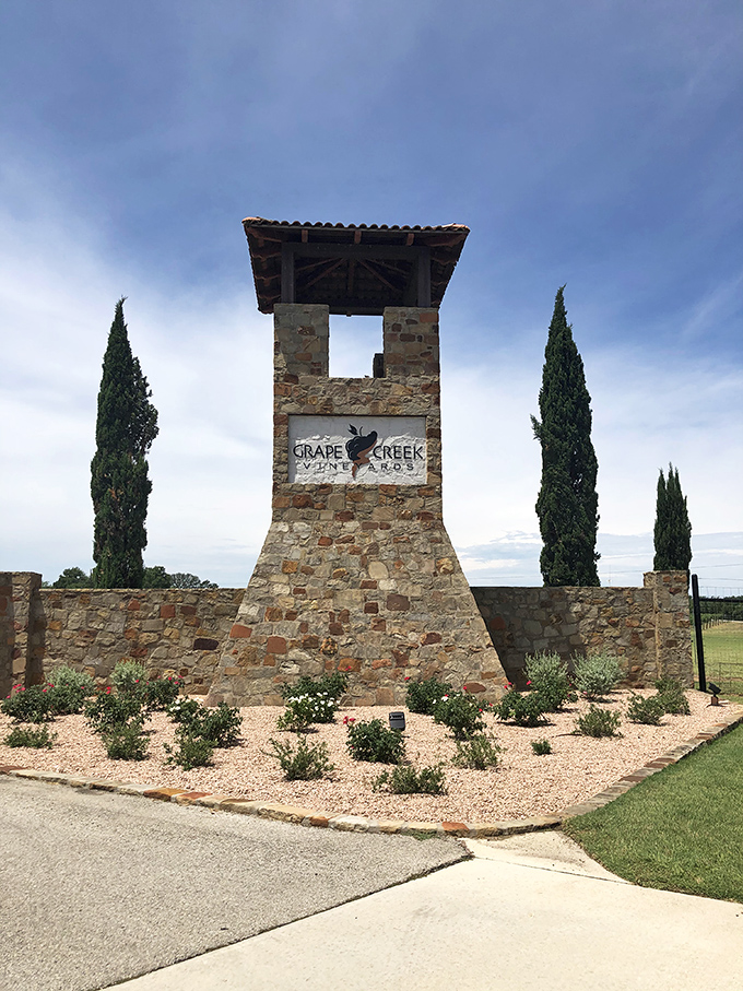 Grape Creek Vineyards' entrance stands like a Mediterranean mirage in the Texas Hill Country. Those cypress trees aren't confused—they're right at home.