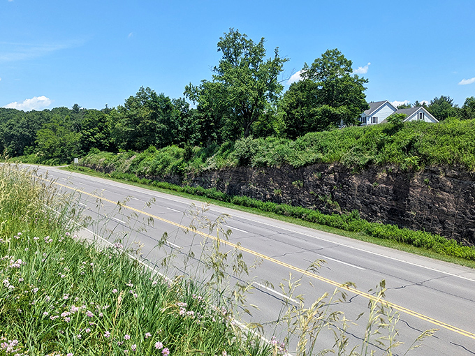 The road cuts through ancient rock formations, a testament to human determination to connect even the most challenging landscapes.