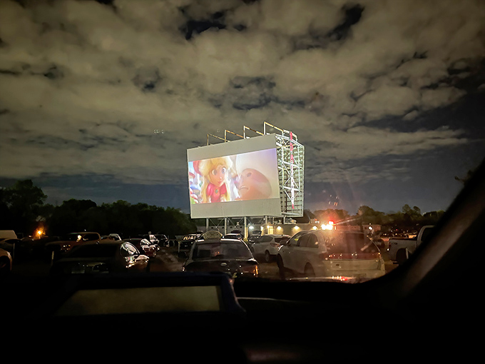 As darkness falls, the illuminated screen works its magic, turning ordinary cars into personal theaters under a canopy of clouds.