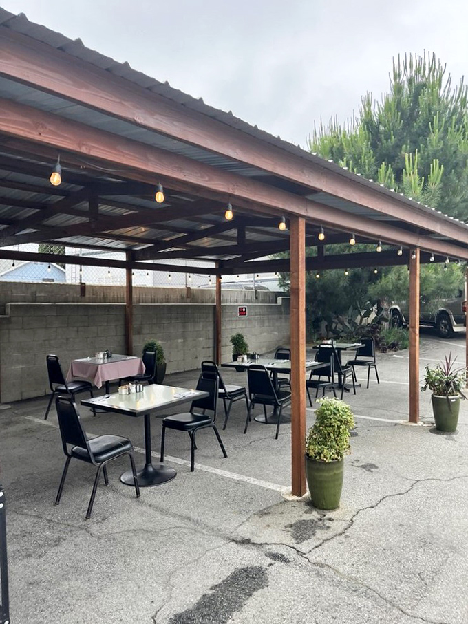 Al fresco dining, California-style. Simple tables under a wooden pergola where string lights promise to twinkle as evening approaches.