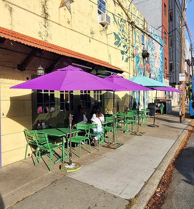Colorful umbrellas and bright green chairs turn the sidewalk into an urban oasis where brunch and people-watching form a perfect weekend pairing.