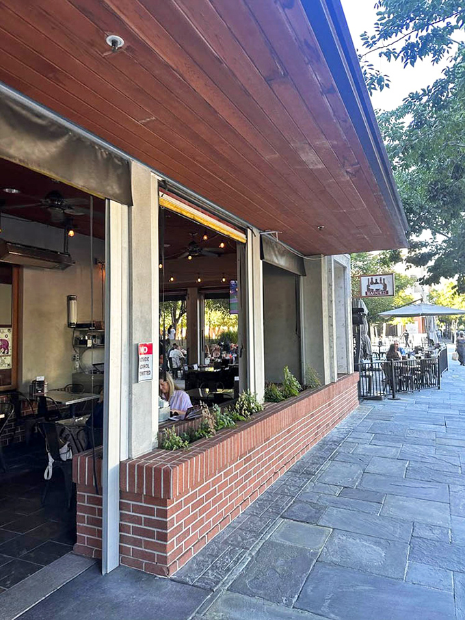 The indoor-outdoor flow creates a seamless California dining experience where barbecue meets fresh air under wooden eaves and string lights.