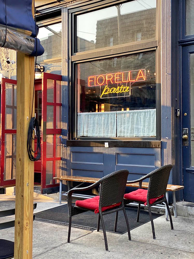 Fiorella's iconic neon sign glows like a beacon for pasta pilgrims, promising Italian delights behind that charming blue facade and inviting outdoor seating.