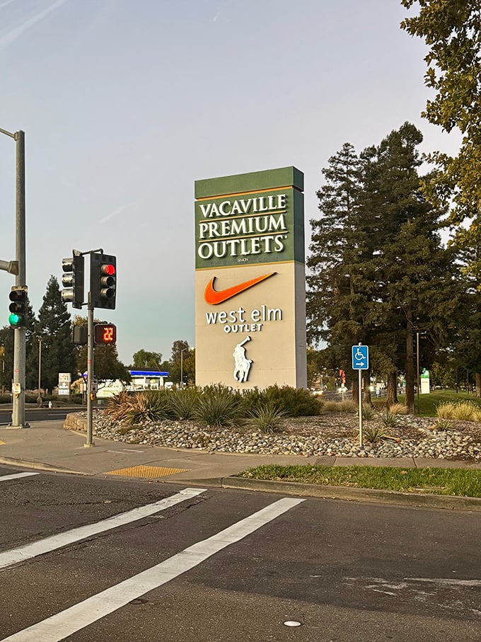 The entrance sign stands like a retail Stonehenge, marking the sacred ground where full prices go to meet their markdown maker.