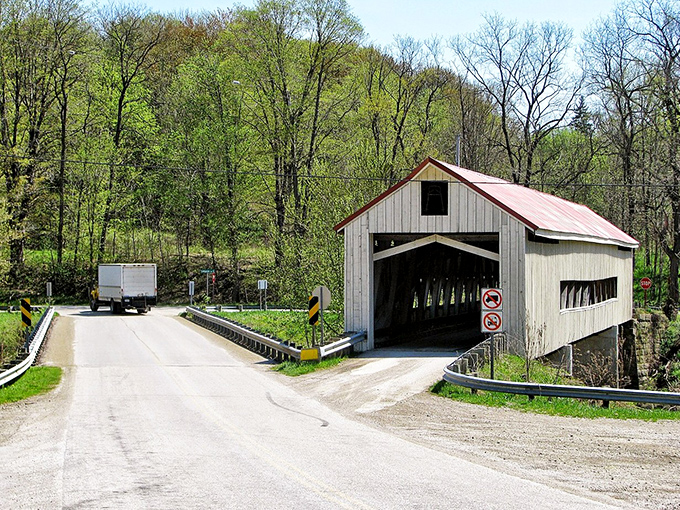 Spring brings renewal to the bridge's surroundings, with fresh greenery providing the perfect contrast to weathered white siding and that signature red roof.