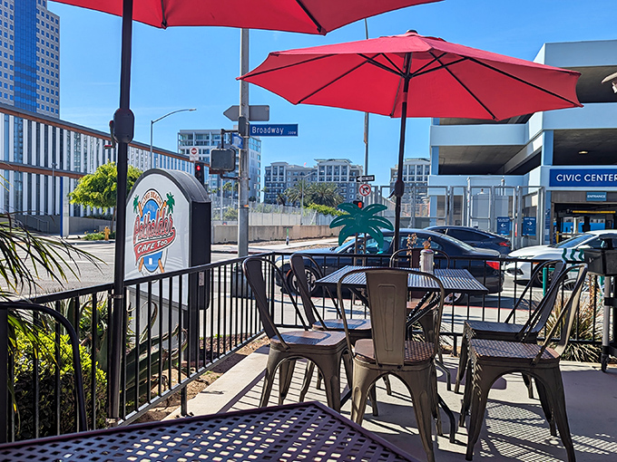 The patio offers urban breakfast theater with red umbrellas providing shade for your morning performance.