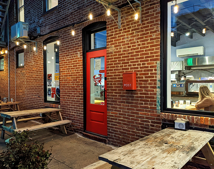 The unassuming exterior with picnic tables offers a hint of the unpretentious seafood paradise waiting just beyond that red door.