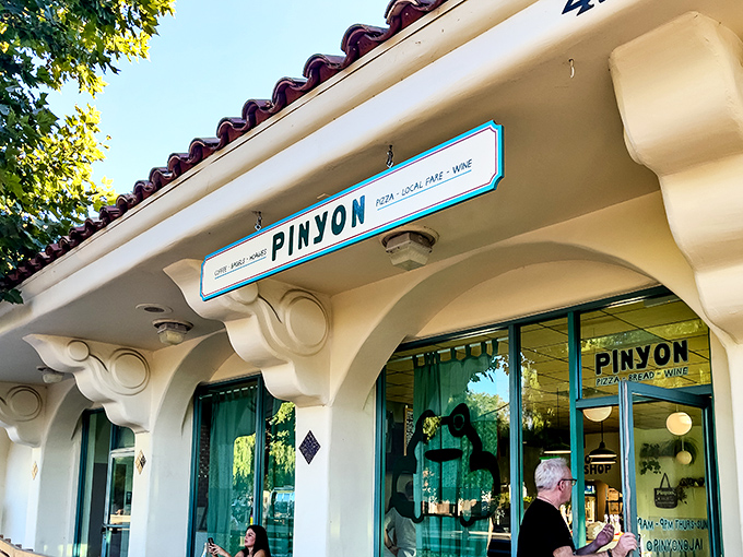 Pinyon's storefront glows with invitation, where pizza, local wine, and the possibility of perfect evening conversations await just beyond those turquoise doors.