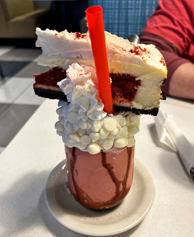 This isn't just a milkshake; it's a carnival that decided to move into a glass. The slice of cake on top is just showing off.