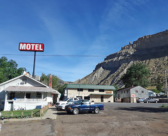 The Riverside Motel sign stands as a beacon of hospitality against the dramatic backdrop of Helper's surrounding cliffs, promising weary travelers a genuine slice of Americana.
