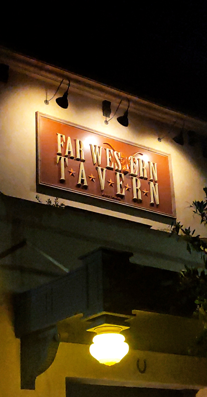 The Far Western Tavern sign glows like a beacon for hungry travelers. Night lighting that says "yes, we're still serving excellence."