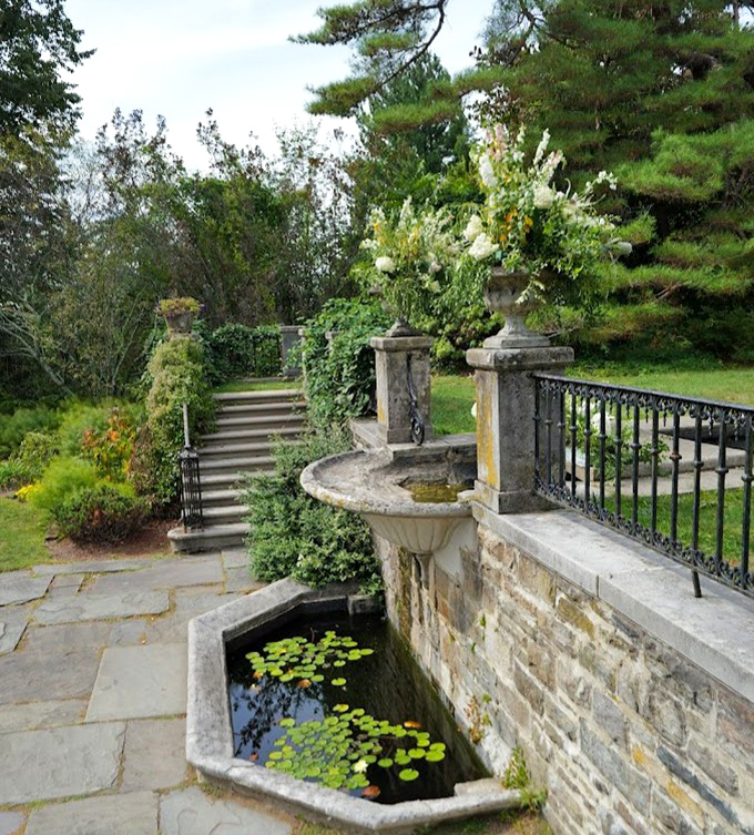 Water and stone create a perfect marriage in this elegant fountain terrace, where lily pads add splashes of green to the reflective surface.