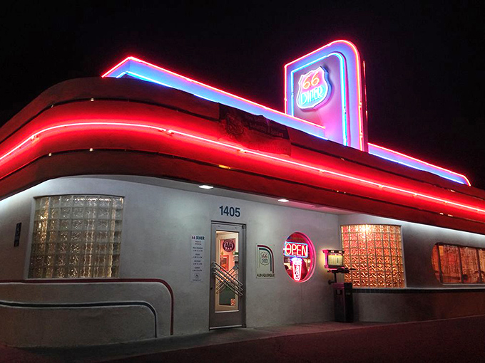 By night, the diner transforms into a neon beacon, its glowing red and blue lights calling to hungry night owls like a retro lighthouse.