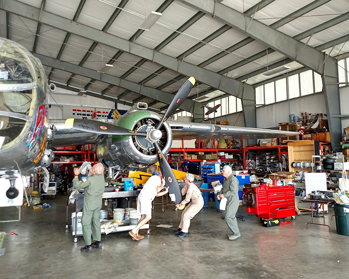 Teamwork makes the dream work as volunteers carefully maneuver a massive propeller. These unsung heroes keep aviation history alive.