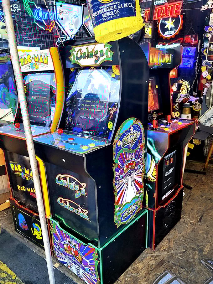 Vintage arcade machines glowing with nostalgia. Pac-Man still chomping after all these years, waiting to eat your quarters and your afternoon.