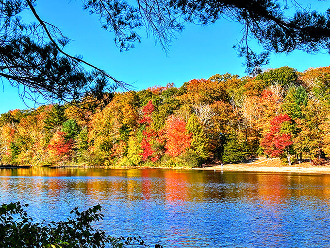 Fall foliage creates nature's fireworks display, reflecting in waters so still they could be mistaken for glass. Peak New England magic.