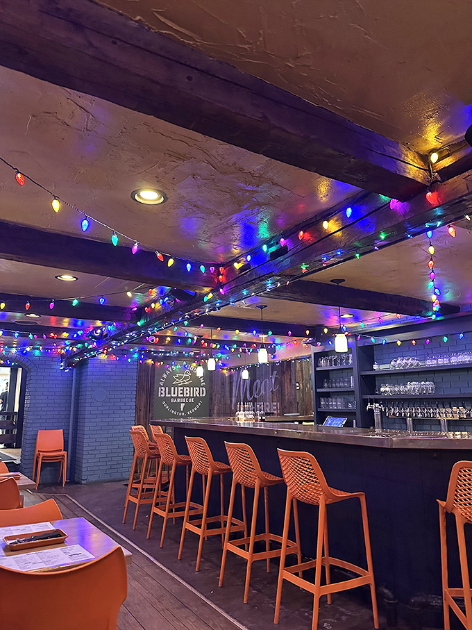 The heart of Bluebird's operation: a bar that beckons with orange stools and twinkling lights. This is where barbecue dreams and cocktail wishes come true.