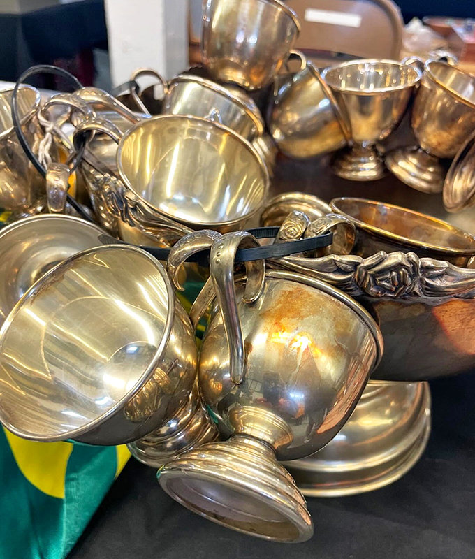 Silver and brass cups tumble together like metallic seashells, each one polished by time and waiting for a second life of dinner parties.
