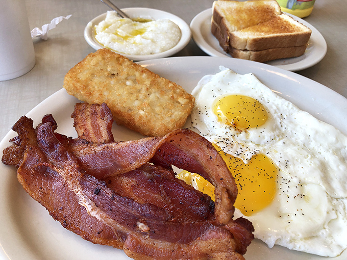 Breakfast perfection on a plate—crispy bacon, sunny eggs, and hash browns that make you question why you ever attempted cooking at home.