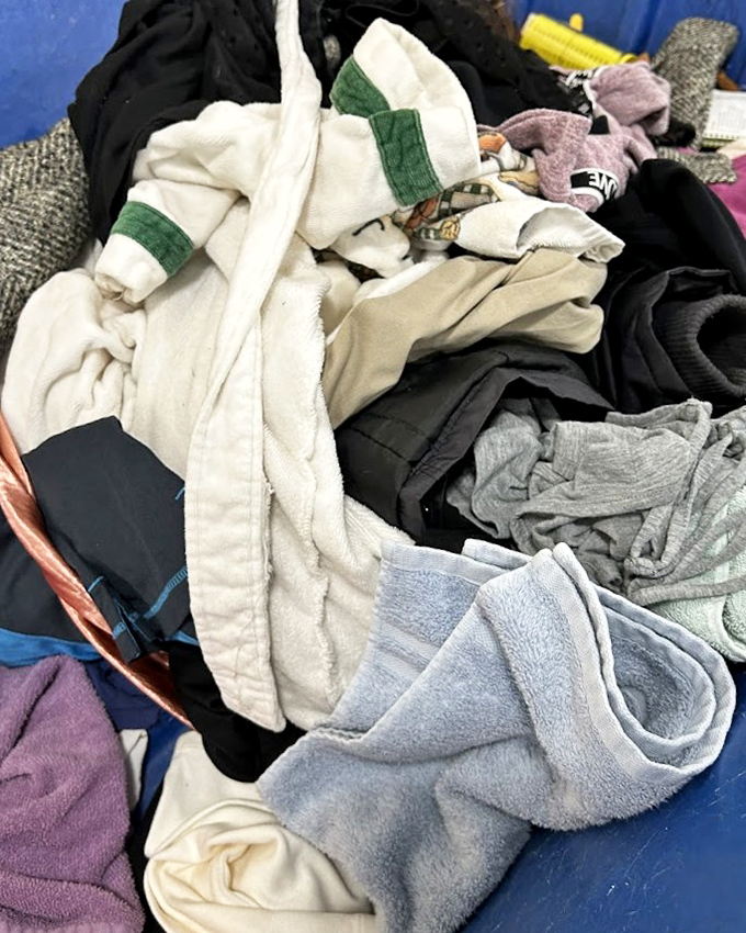 Textiles in various states of repose create a fabric landscape where cotton, polyester, and wool mingle in unexpected harmony.