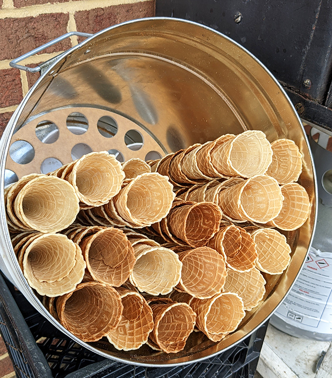 Fresh waffle cones stacked like edible gold, waiting to cradle scoops of ice cream in a ritual that's remained unchanged while empires have risen and fallen.