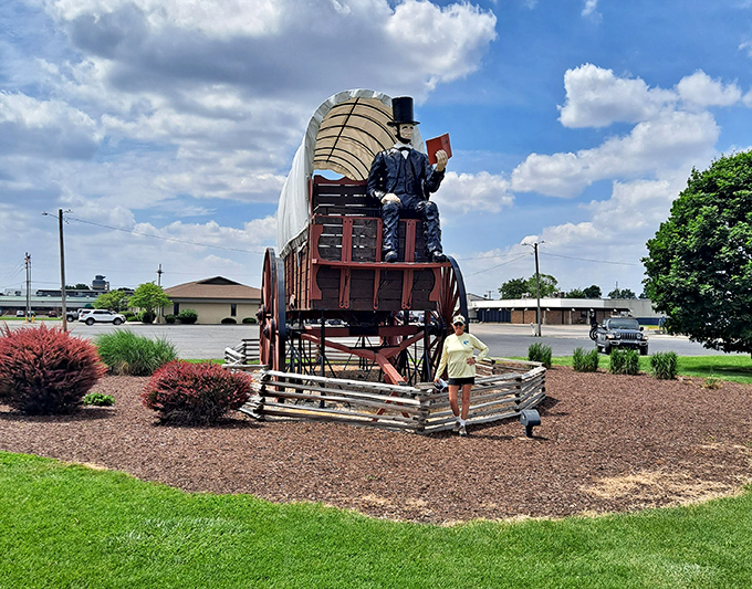Morning light bathes the wagon in golden hues. Without its canvas covering, you can appreciate the craftsmanship that went into creating this wooden wonder.