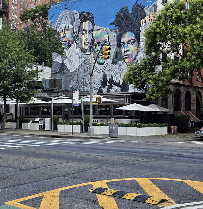 From across the street, Empire Diner sits beneath a vibrant mural, the chrome-and-white landmark holding its own against the colorful urban backdrop.
