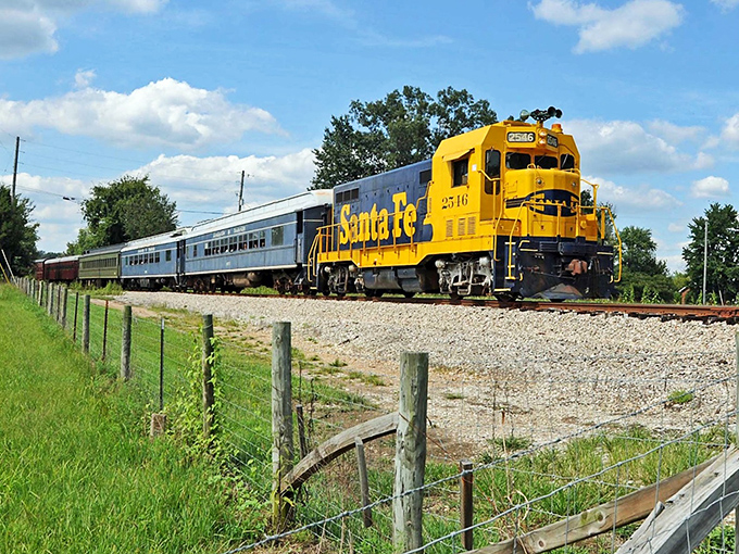 The bright yellow Santa Fe locomotive pulls passenger cars through Kentucky farmland, a moving postcard from America's transportation heritage.