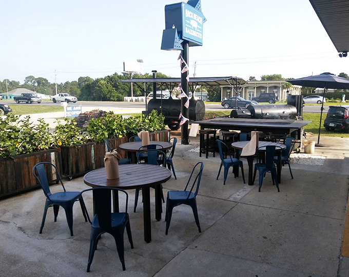 Outdoor dining with a side of smoker envy. Those metal tables have witnessed more food euphoria than a cooking show highlight reel.