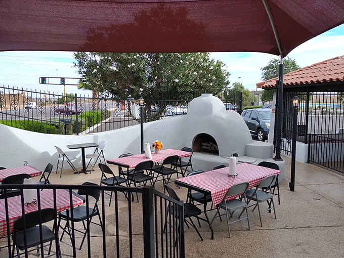 The charming outdoor patio with checkered tablecloths and an adobe oven creates perfect Arizona dining al fresco vibes.