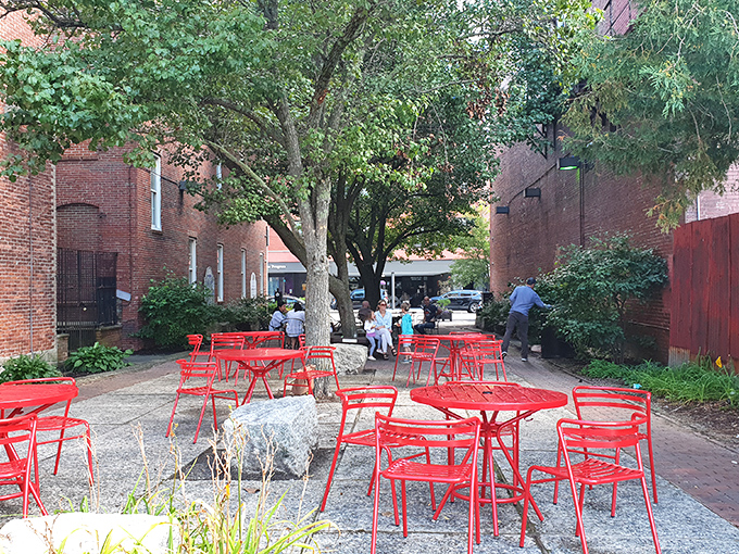 Those red chairs aren't just seating; they're invitations to linger in a courtyard where food comas are welcomed and encouraged.