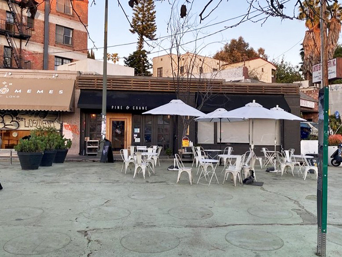 Outdoor seating transforms the sidewalk into an al fresco dining room with umbrella-shaded tables awaiting guests.