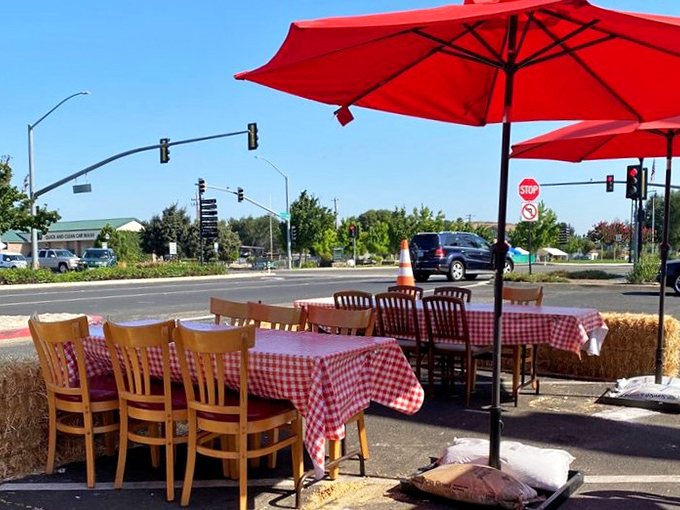 Outdoor seating with hay bales and red umbrellas&mdash;because sometimes the best dining room has no walls at all.