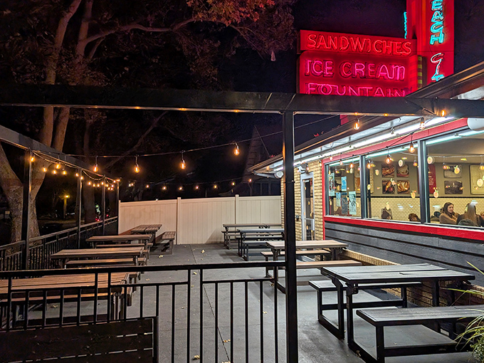 As night falls, Peach City's outdoor seating area transforms into a twinkling oasis where string lights and neon signs create the perfect ambiance for summer evenings.