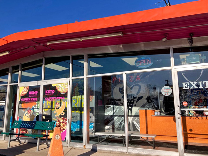 The storefront's colorful exterior and alternative crust options advertised in the window invite dietary-restricted pizza lovers to join the party.