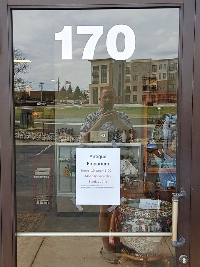 The store hours sign reflects in the glass, a portal to the past that operates conveniently in the present, six days a week.