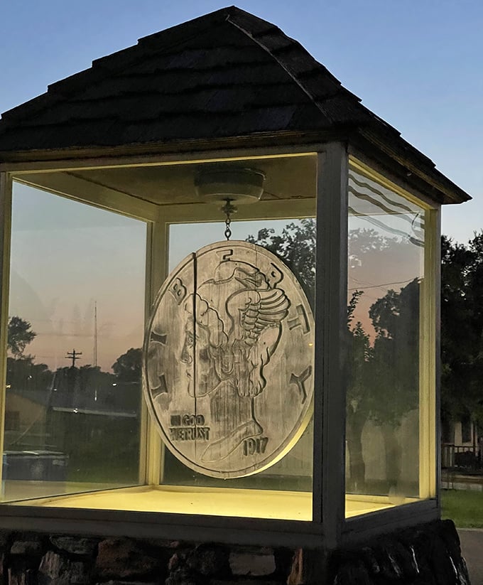 Sunset creates a warm amber glow around the suspended coin, turning this roadside oddity into something surprisingly beautiful as day fades to night.