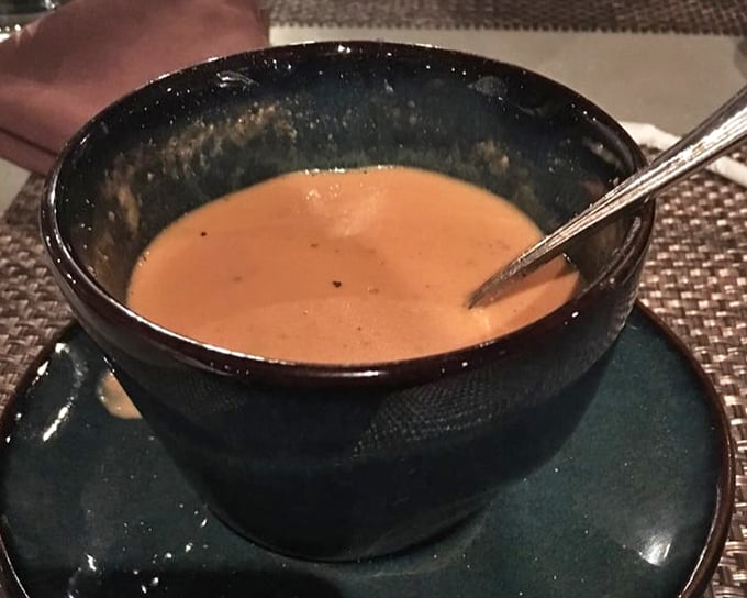 Tomato soup in a rustic bowl that channels childhood comfort while adding grown-up depth—like finding your favorite teddy bear has suddenly developed excellent taste in wine.