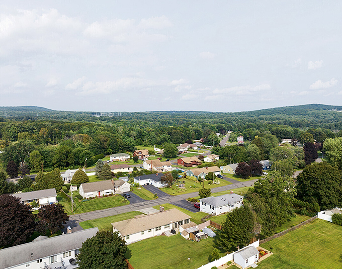 From above, Ludlow reveals itself as a perfect patchwork of homes nestled among trees, with rolling hills creating a natural embrace around this charming community.