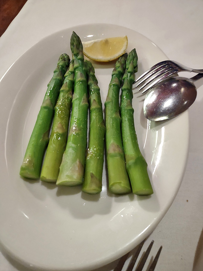 Asparagus spears, vibrant green and perfectly cooked, with a wedge of lemon&mdash;because even side dishes deserve respect at a serious steakhouse.