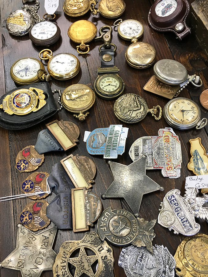 Pocket watches, badges, and vintage pins scattered like someone emptied out every grandfather's dresser drawer in the best possible way.