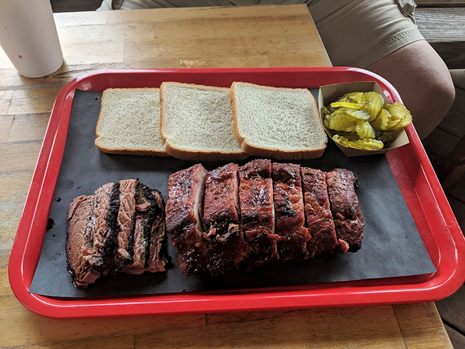 Brisket sliced thicker than a good novel, with a smoke ring that tells tales of patience. The pickle cup is just a bonus character in this meaty story. 
