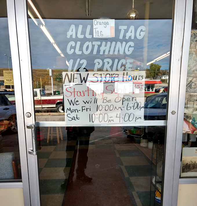 The window sign announces half-price clothing and store hours, but the real message is clear: treasure hunting awaits inside.