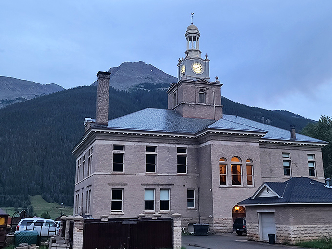 The County Historical Museum glows at dusk, its clock tower illuminated against mountain shadows&mdash;a timekeeper of Silverton's rich mining legacy.