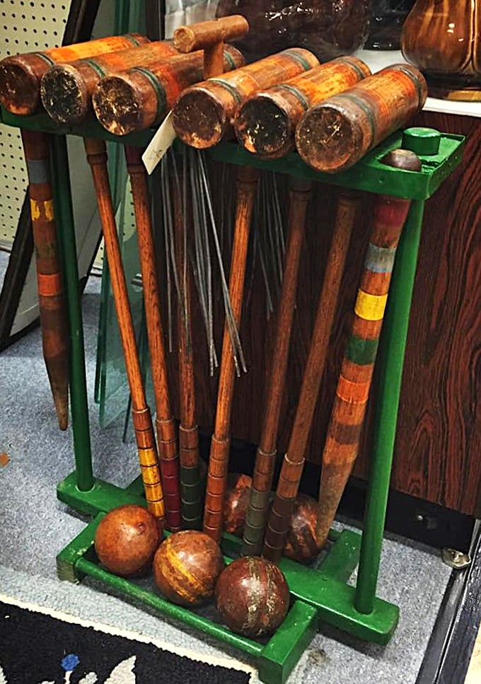 Vintage croquet sets lean casually against their stand, ready to transform any modern lawn gathering into a scene from "The Great Gatsby."