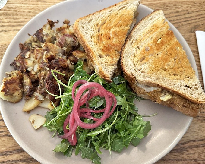This sandwich isn't just grilled; it's transformed—crispy exterior giving way to melty interior, with those pickled red onions cutting through the richness like a well-timed punchline.